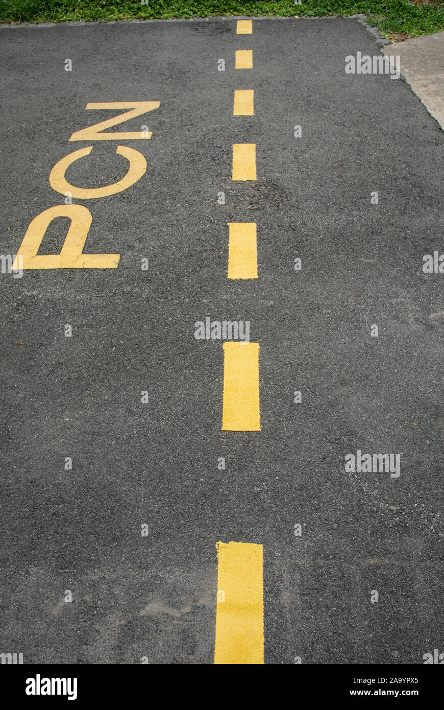 Yellow 'PCN' sign and lines on asphalt road Stock Photo - Alamy