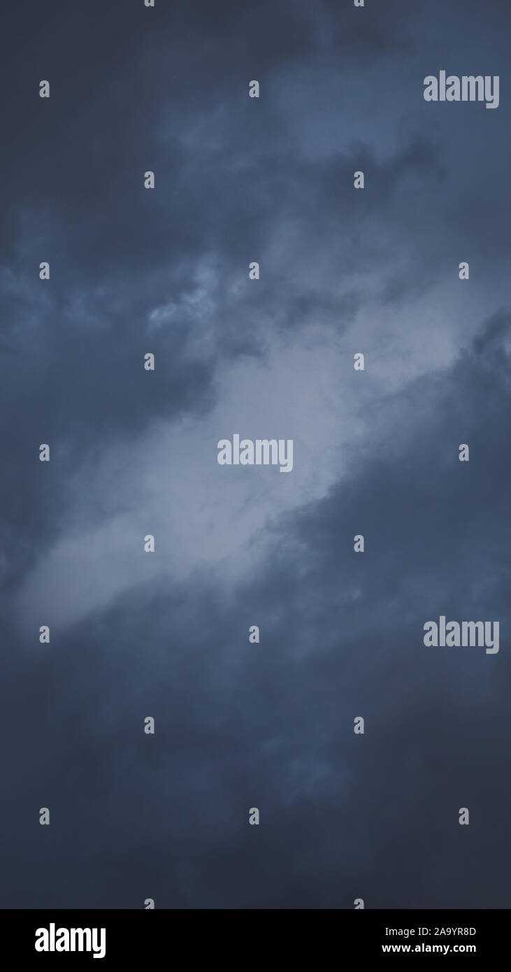 Dark rainy clouds with one lighter part in the middle Stock Photo - Alamy