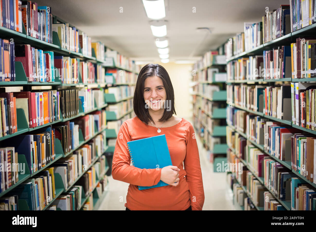 In the library - pretty female student with books working in a high ...