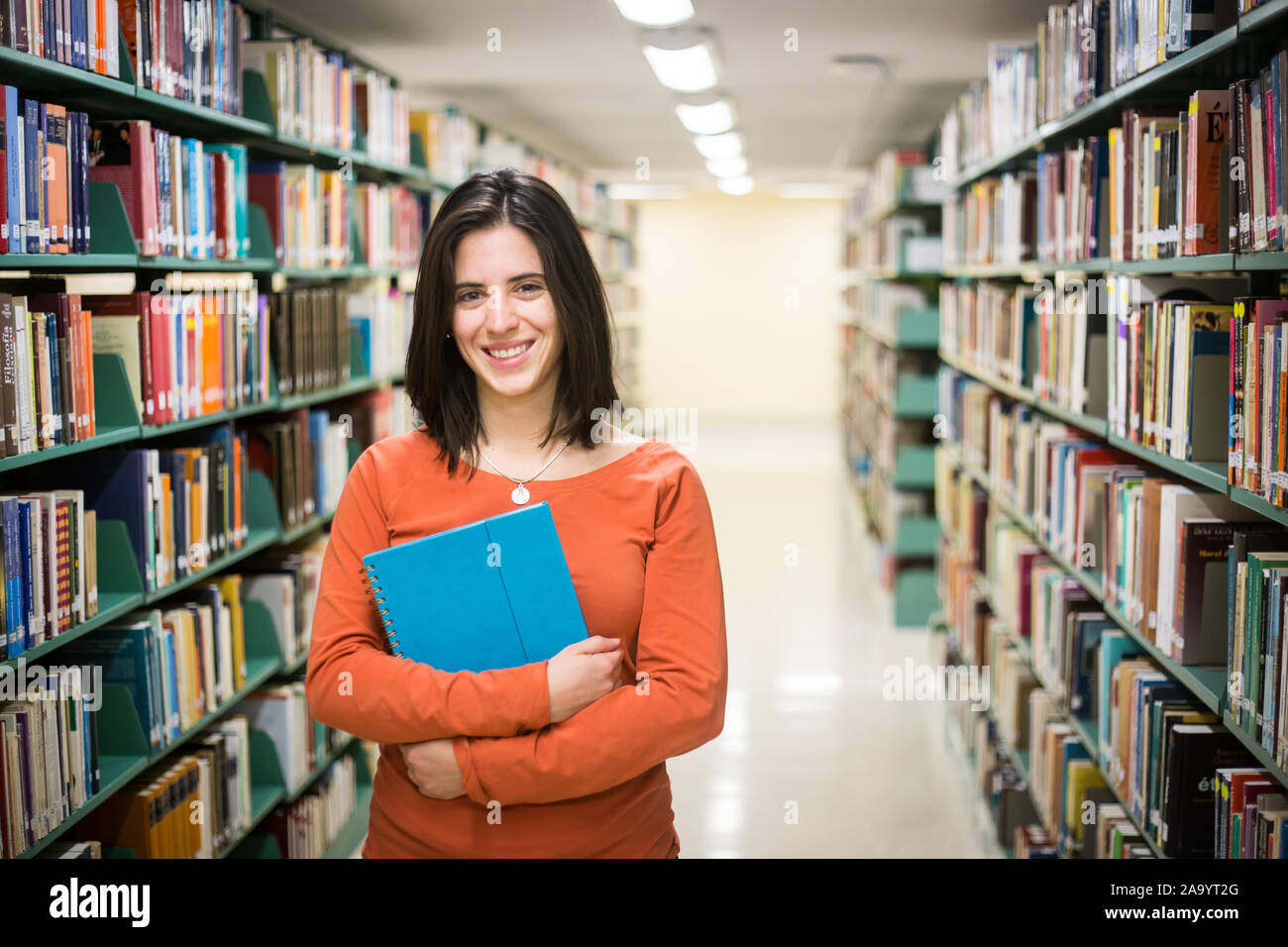 In the library - pretty female student with books working in a high ...