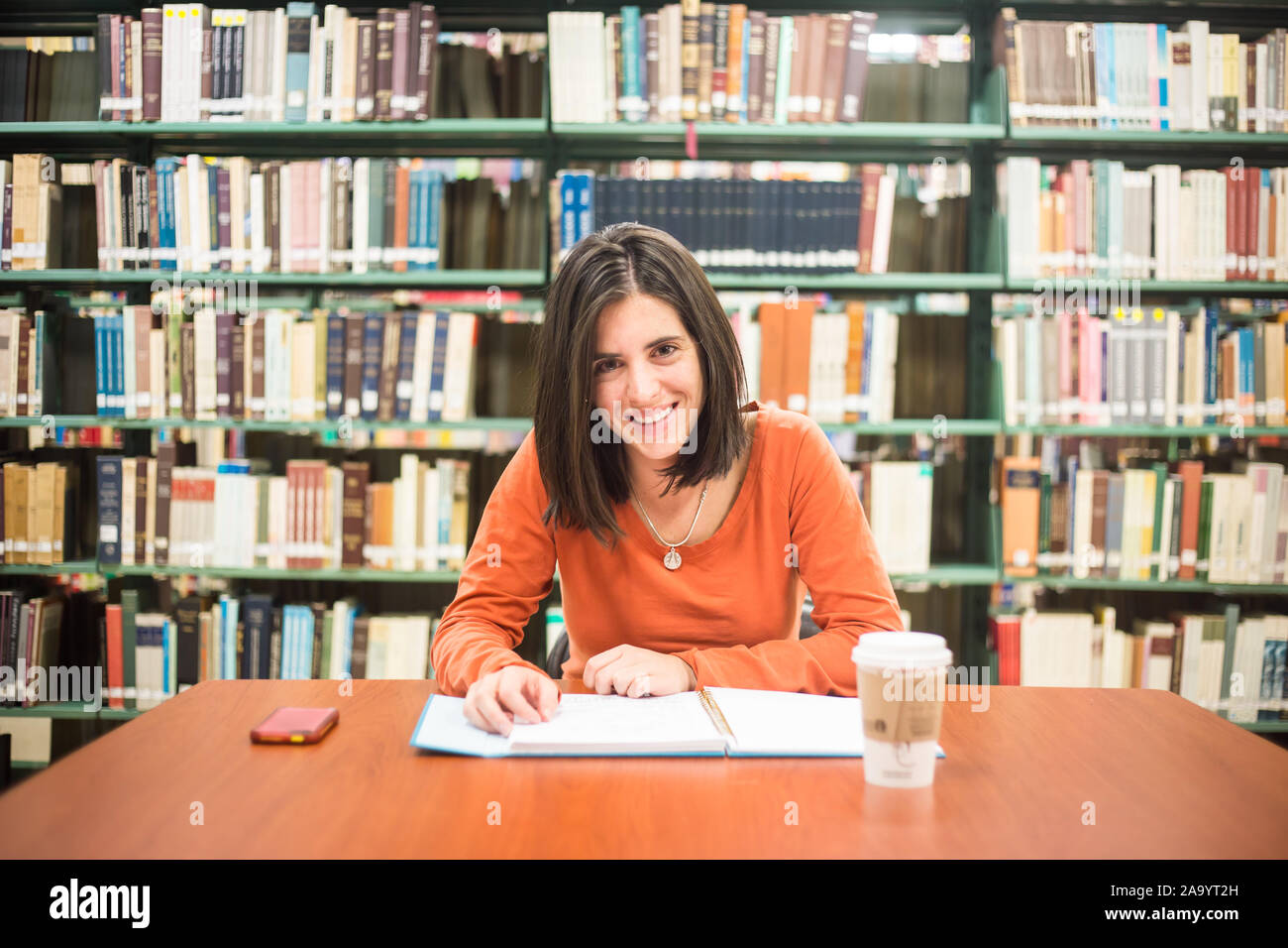 In the library - pretty female student with books working in a high ...