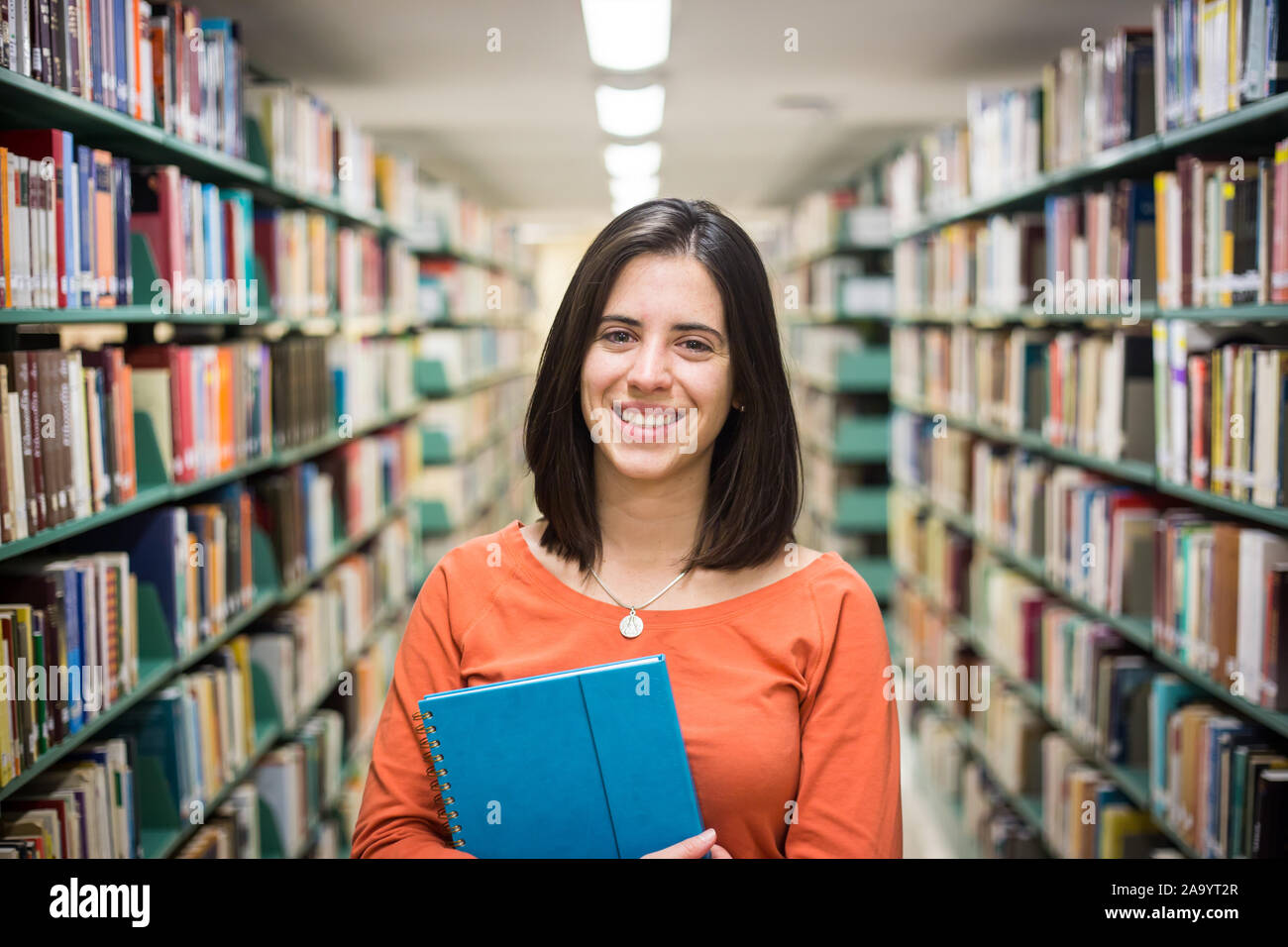 In the library - pretty female student with books working in a high ...