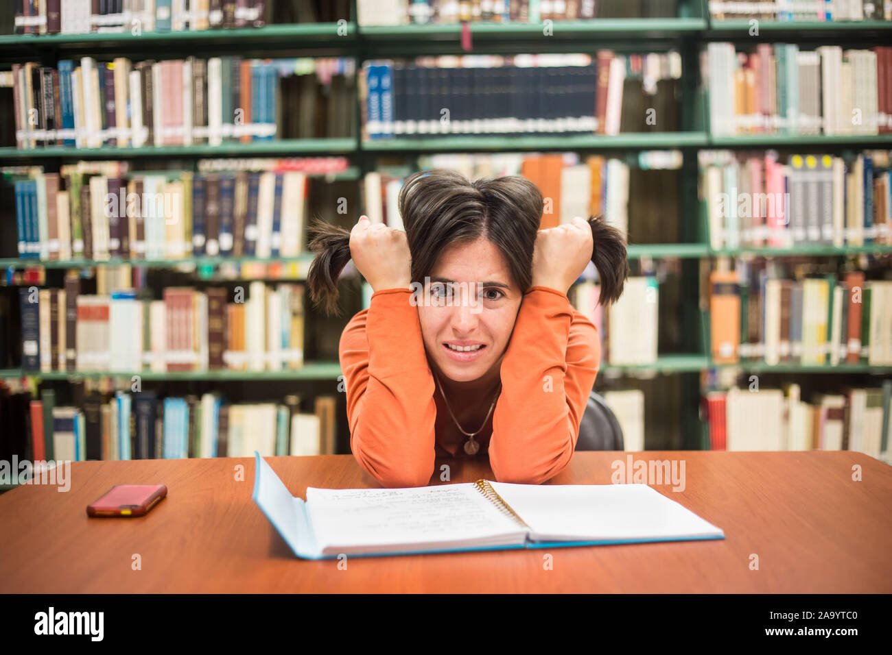In the library - stress pretty female student with books working in a ...
