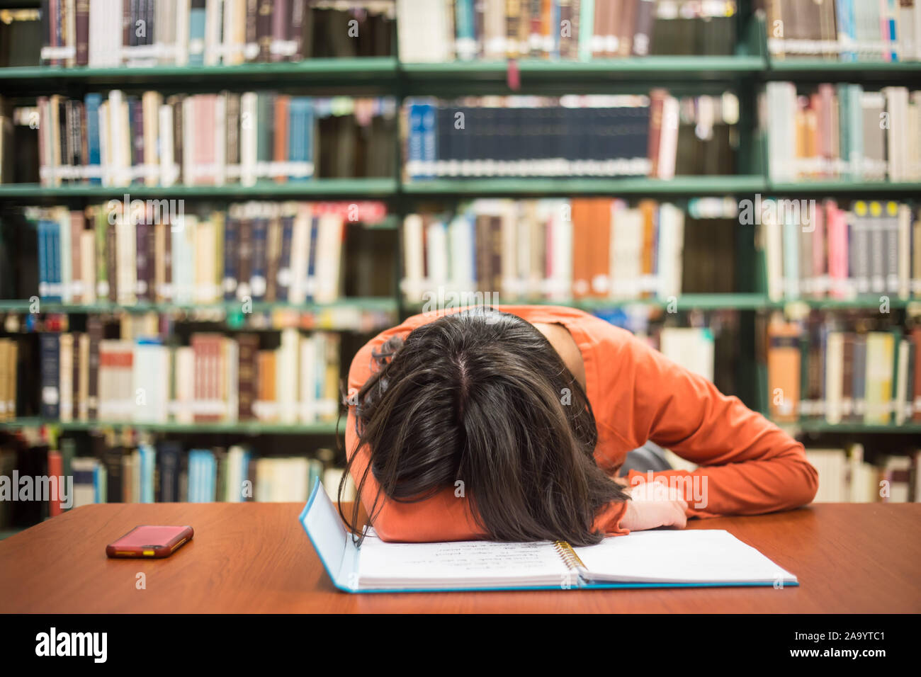 In the library - lazy bored pretty female student with books working in ...