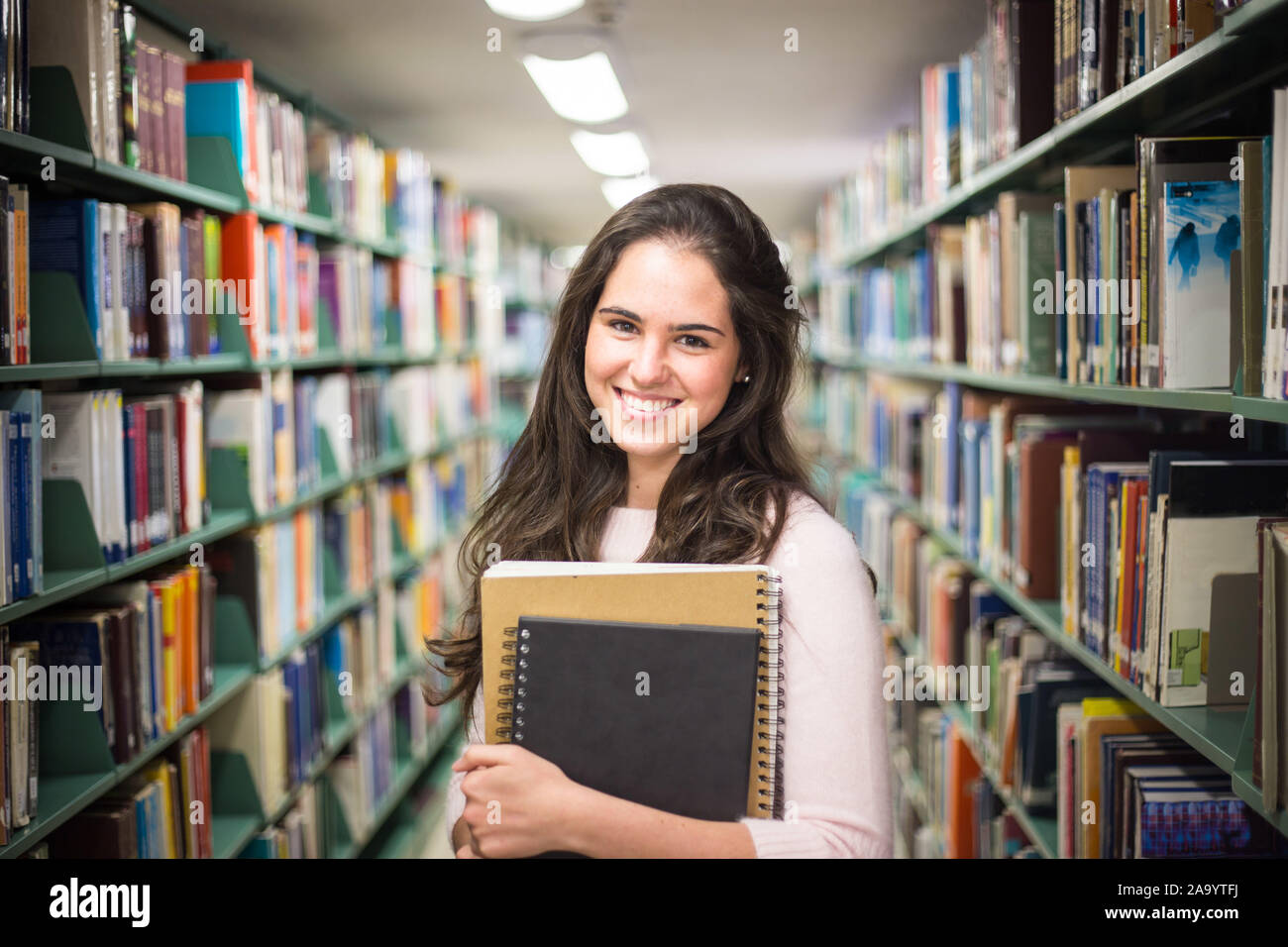 In the library - pretty female student with books working in a high ...