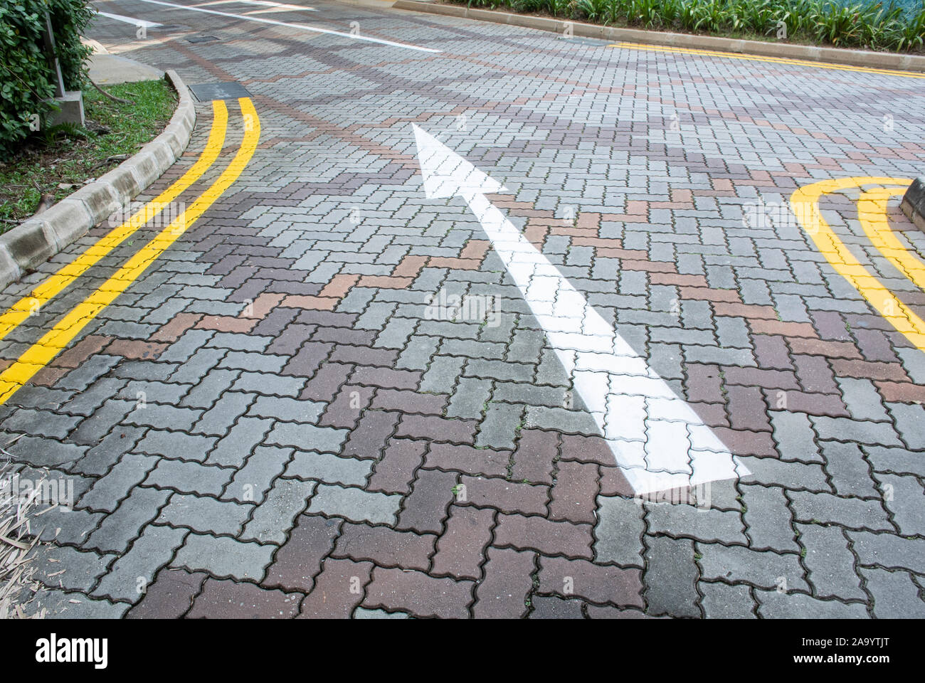 White arrow and double yellow lines painted on interlocking concrete ...