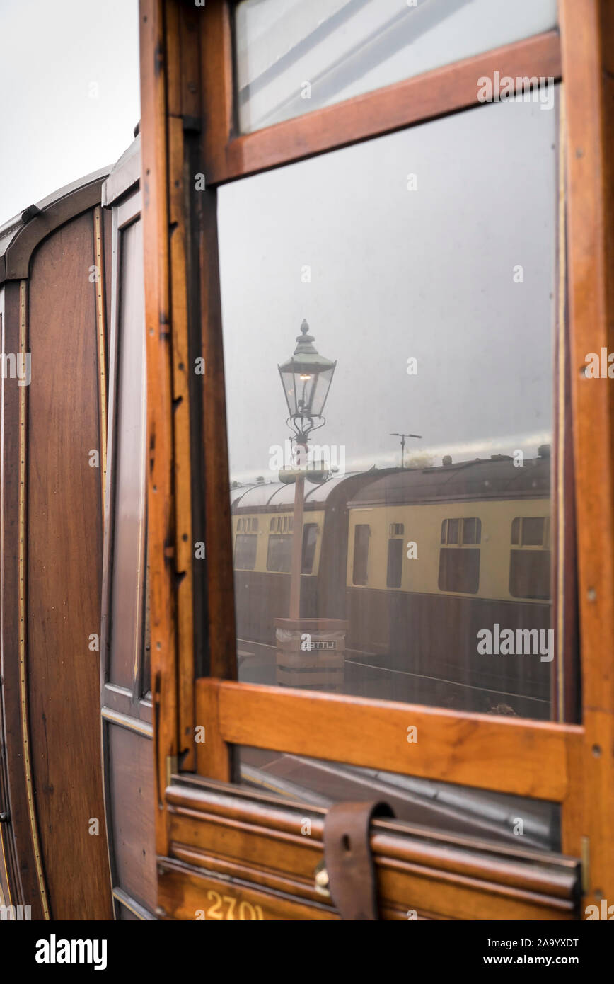 Old-fashioned gas lamp & vintage train reflection in open door window ...