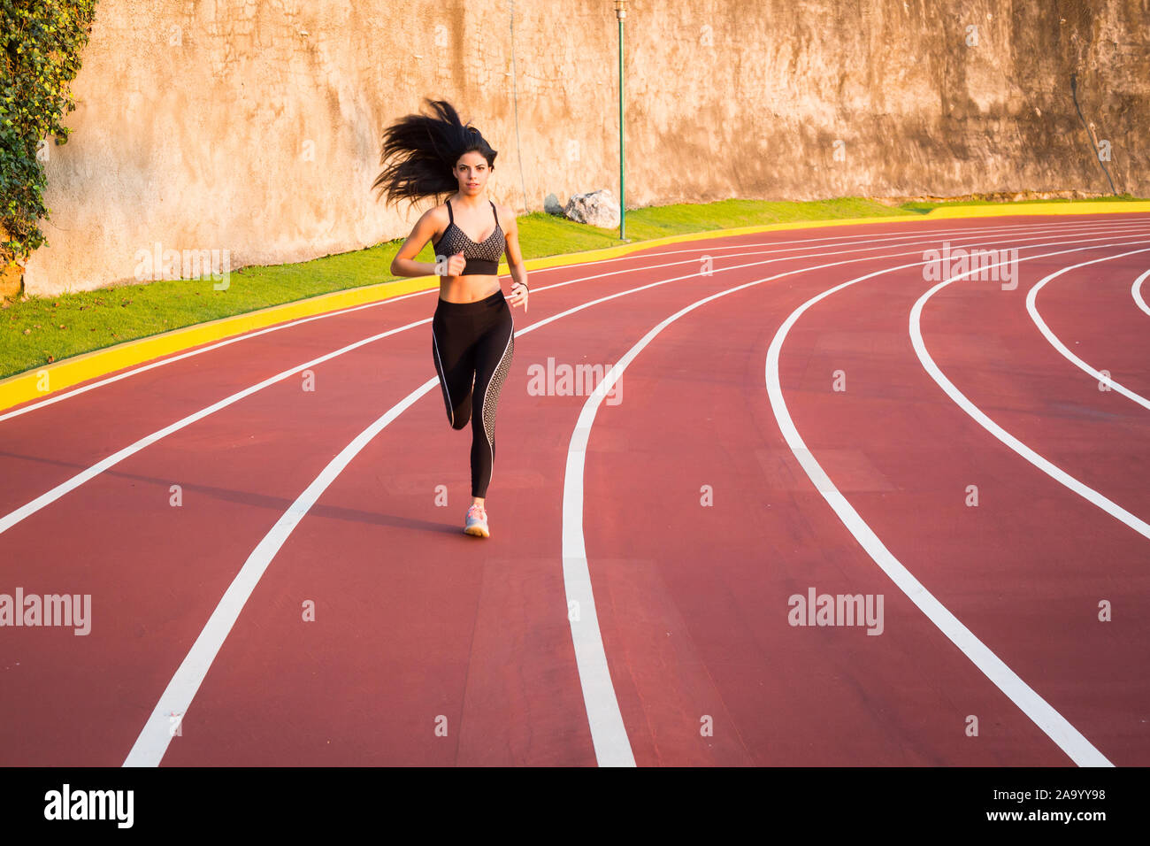 Young woman runner running race on athletics track Stock Photo - Alamy
