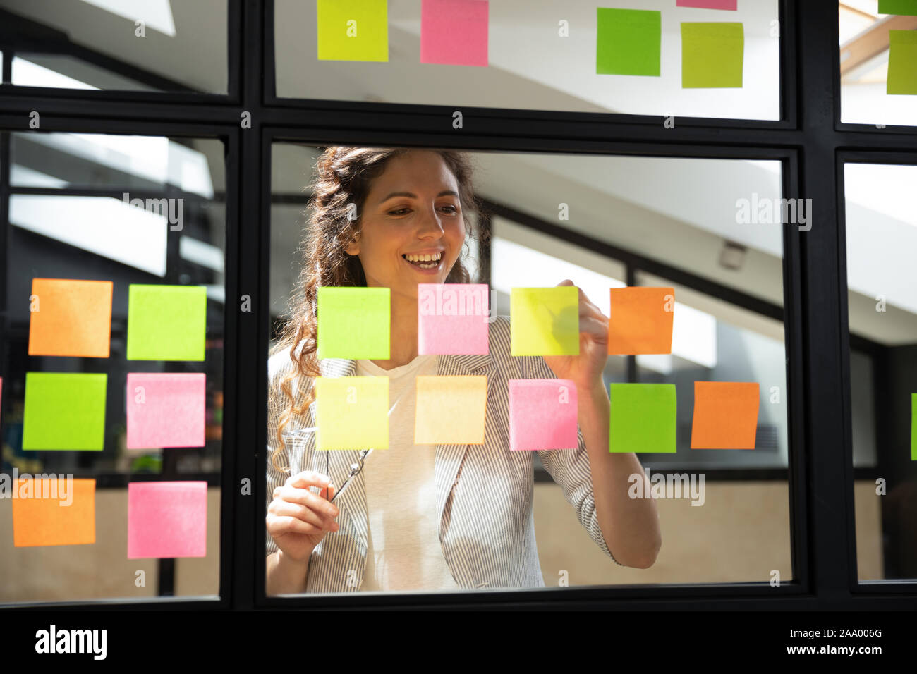 Happy female scrum master writing tasks on sticky paper notes Stock ...