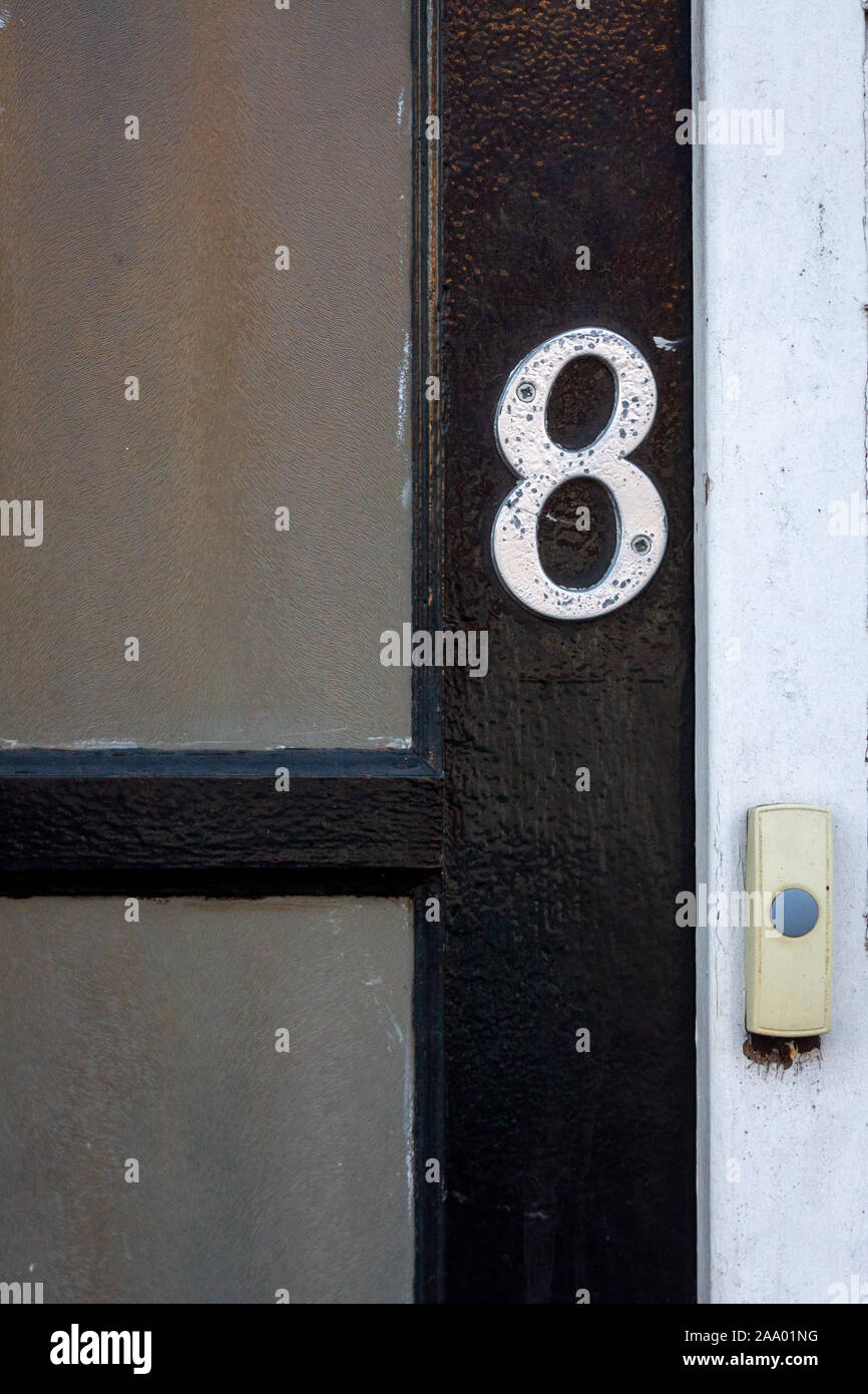 House number 8 with the eight in white on a dark and dingy front door ...