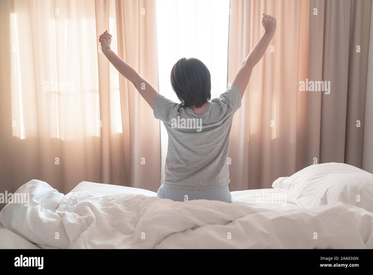 Woman stretching in bed after wake up, back view Stock Photo - Alamy
