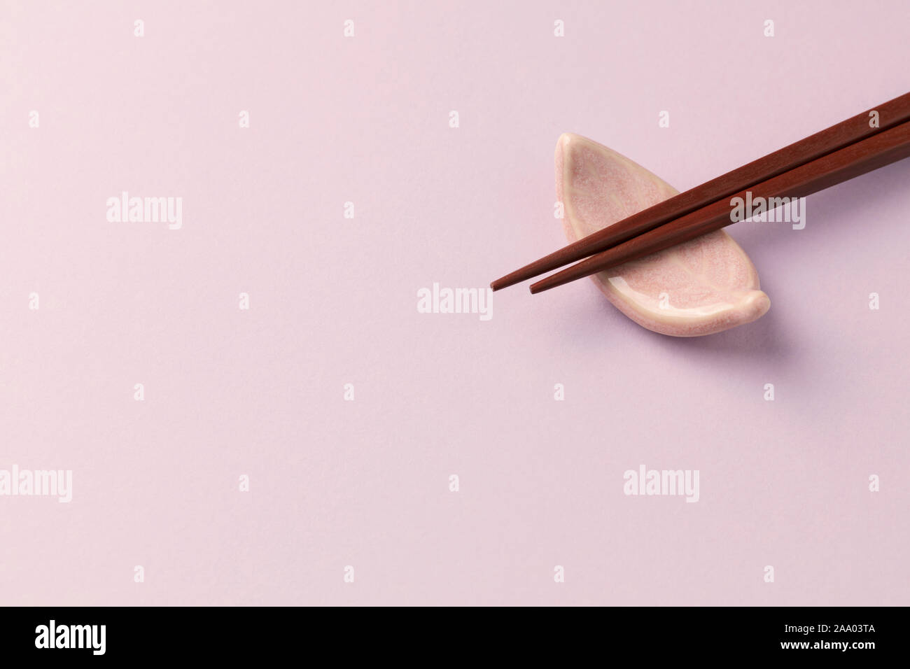 Wooden chopsticks and chopstick rest on bright paper background. Close ...