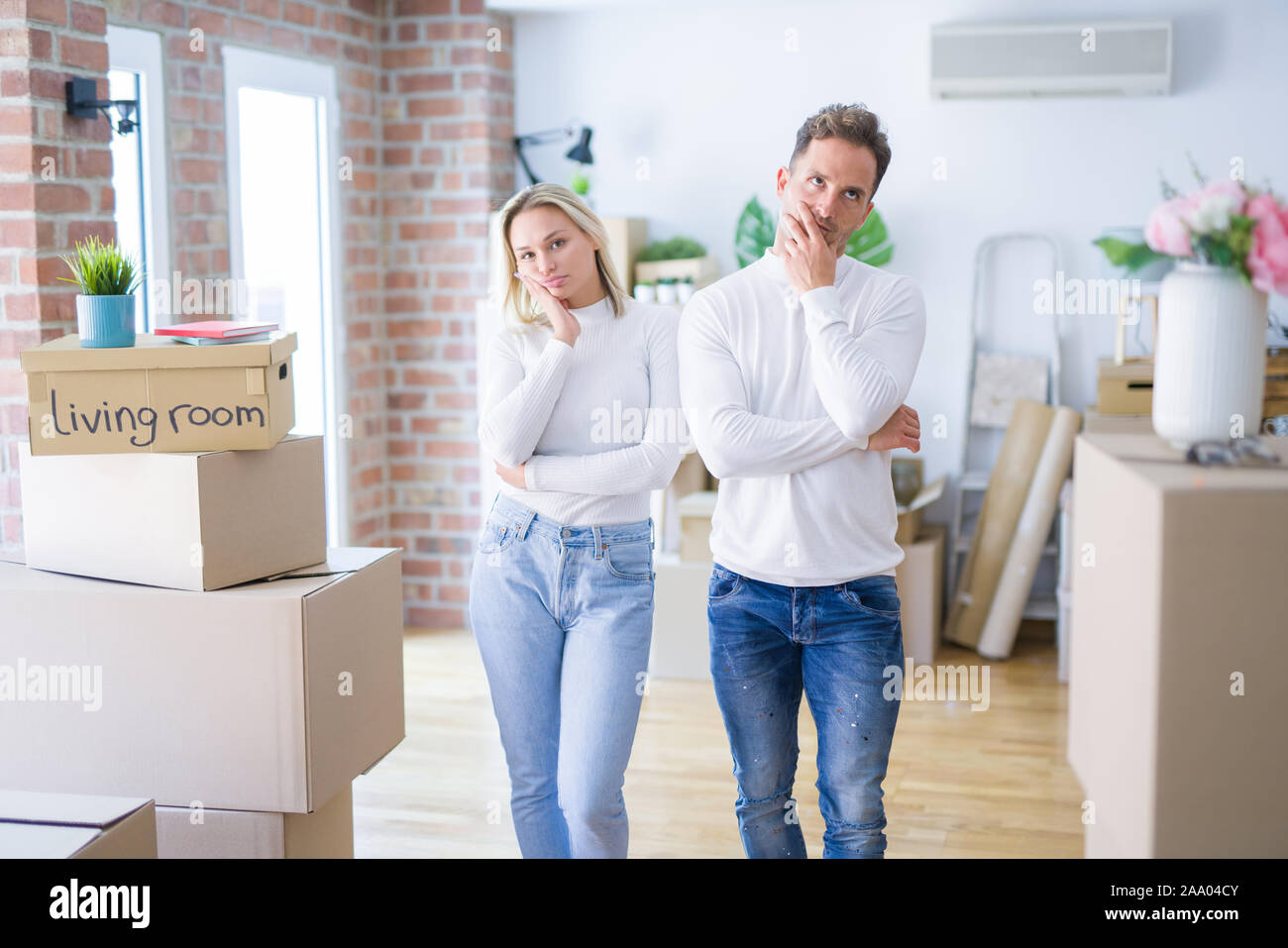 Young beautiful couple standing at new home around cardboard boxes ...