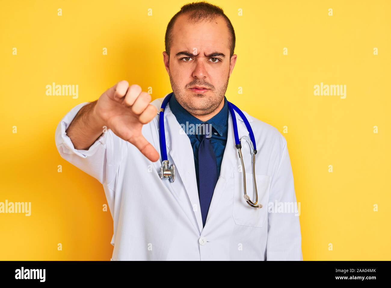 Young doctor man wearing coat and stethoscope standing over isolated ...