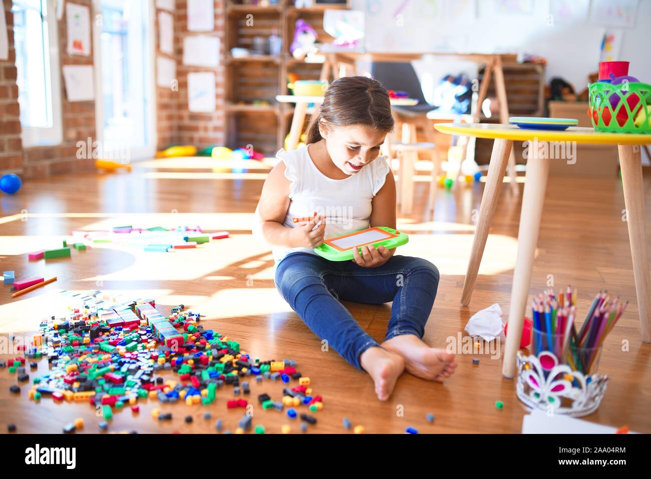 Adorable toddler drawing using digital board around lots of toys at ...