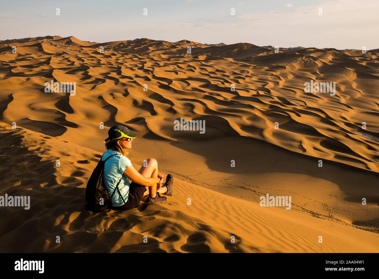 Tourist in Kumtag desert dunes at sunset from the biggest Taklamakan ...