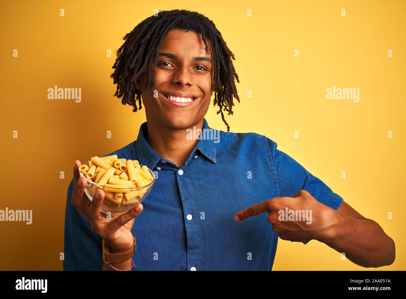 Afro american man with dreadlocks holding pasta macaroni over isolated ...