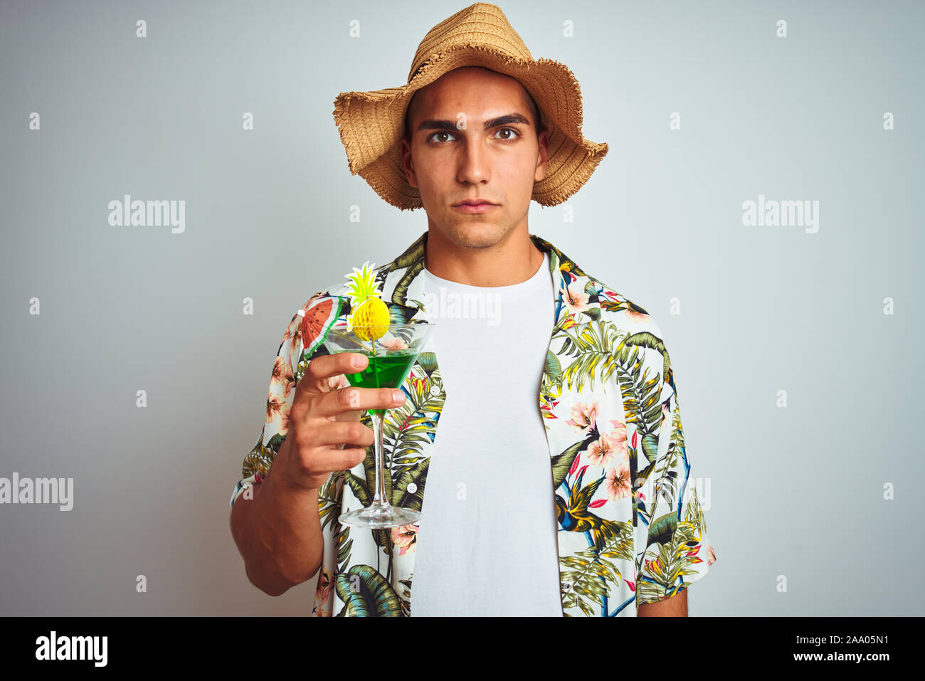Young handsome man drinking cocktail on holiday over white isolated ...
