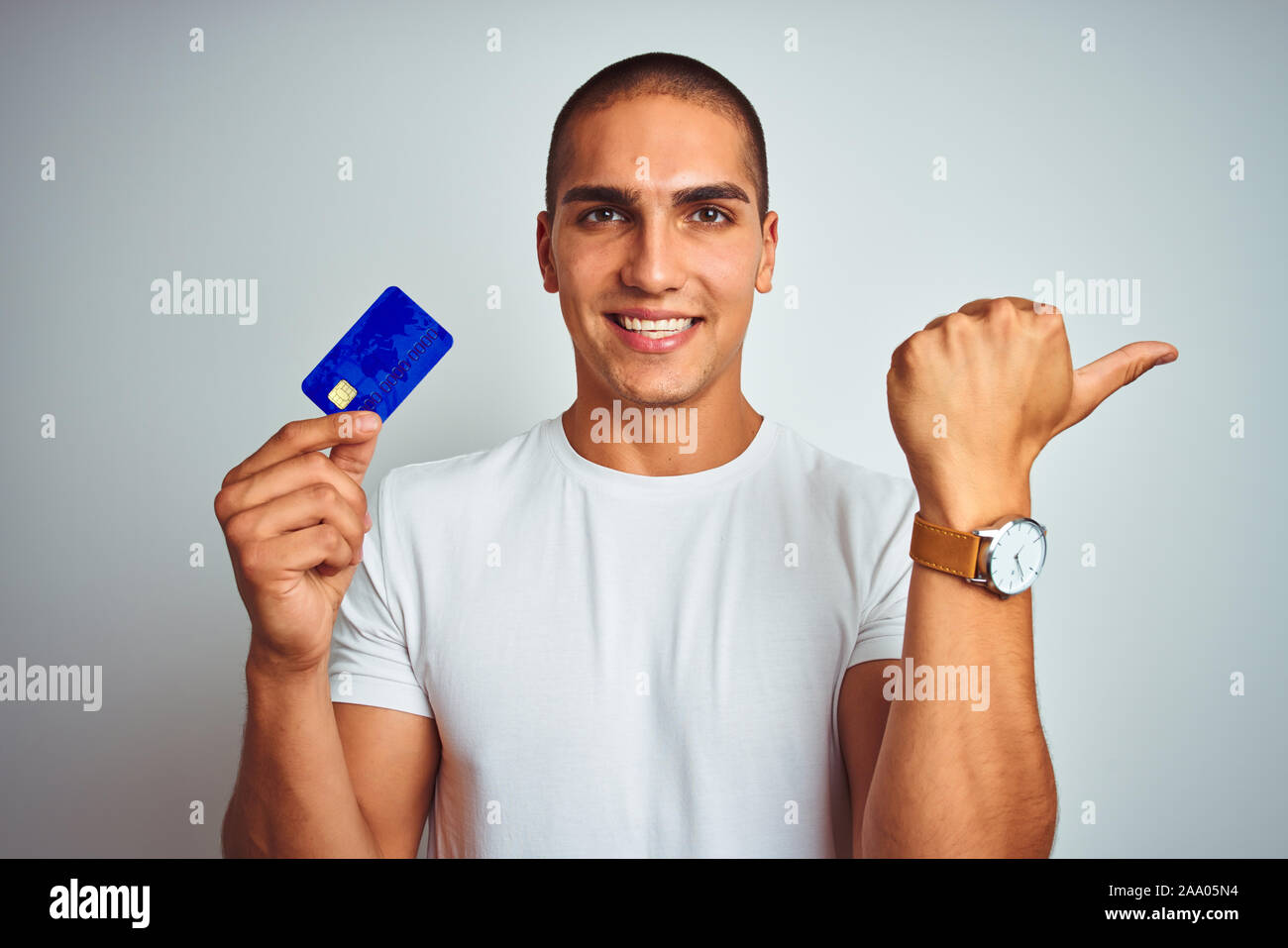 Young handsome man holding credit card over white isolated background ...