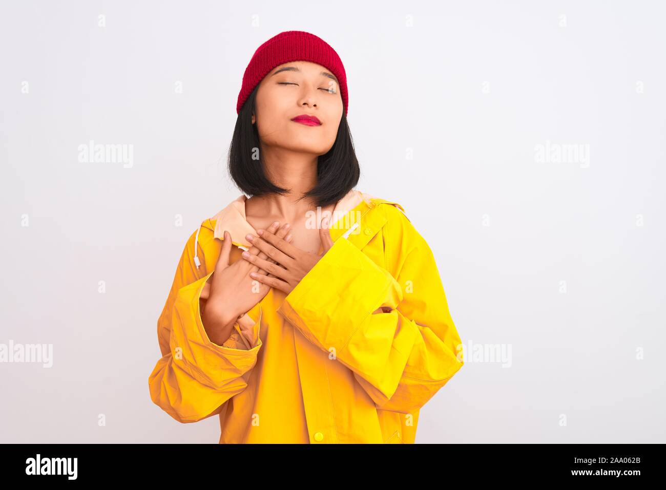 Young beautiful chinese woman wearing raincoat and wool cap over ...
