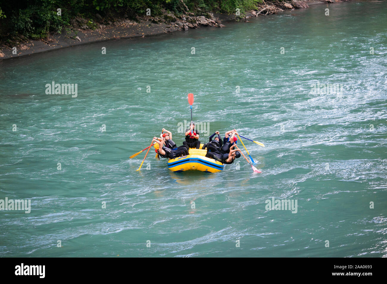 Group of happy people with guide whitewater rafting and rowing on river ...