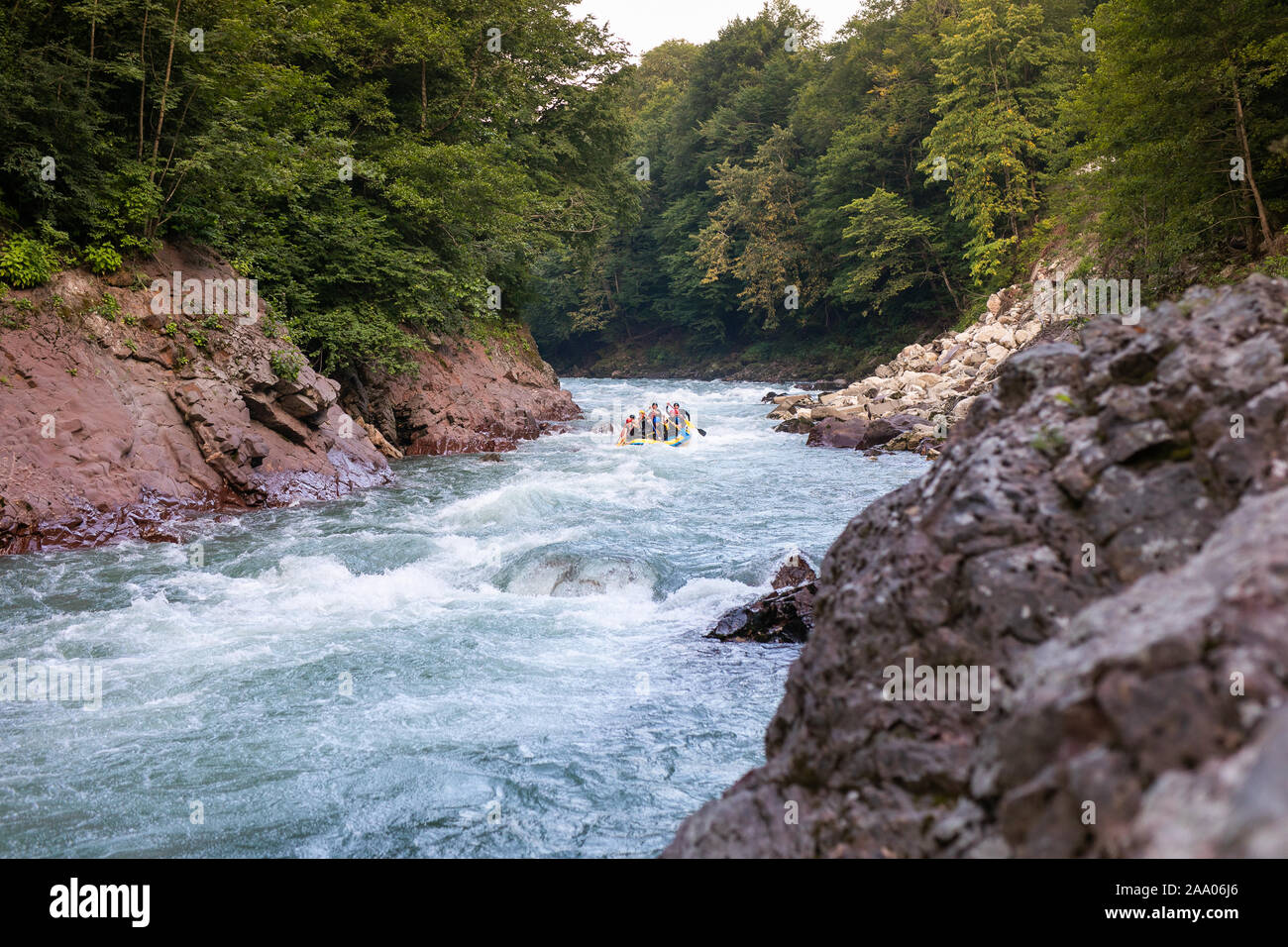 Group of happy people with guide whitewater rafting and rowing on river ...