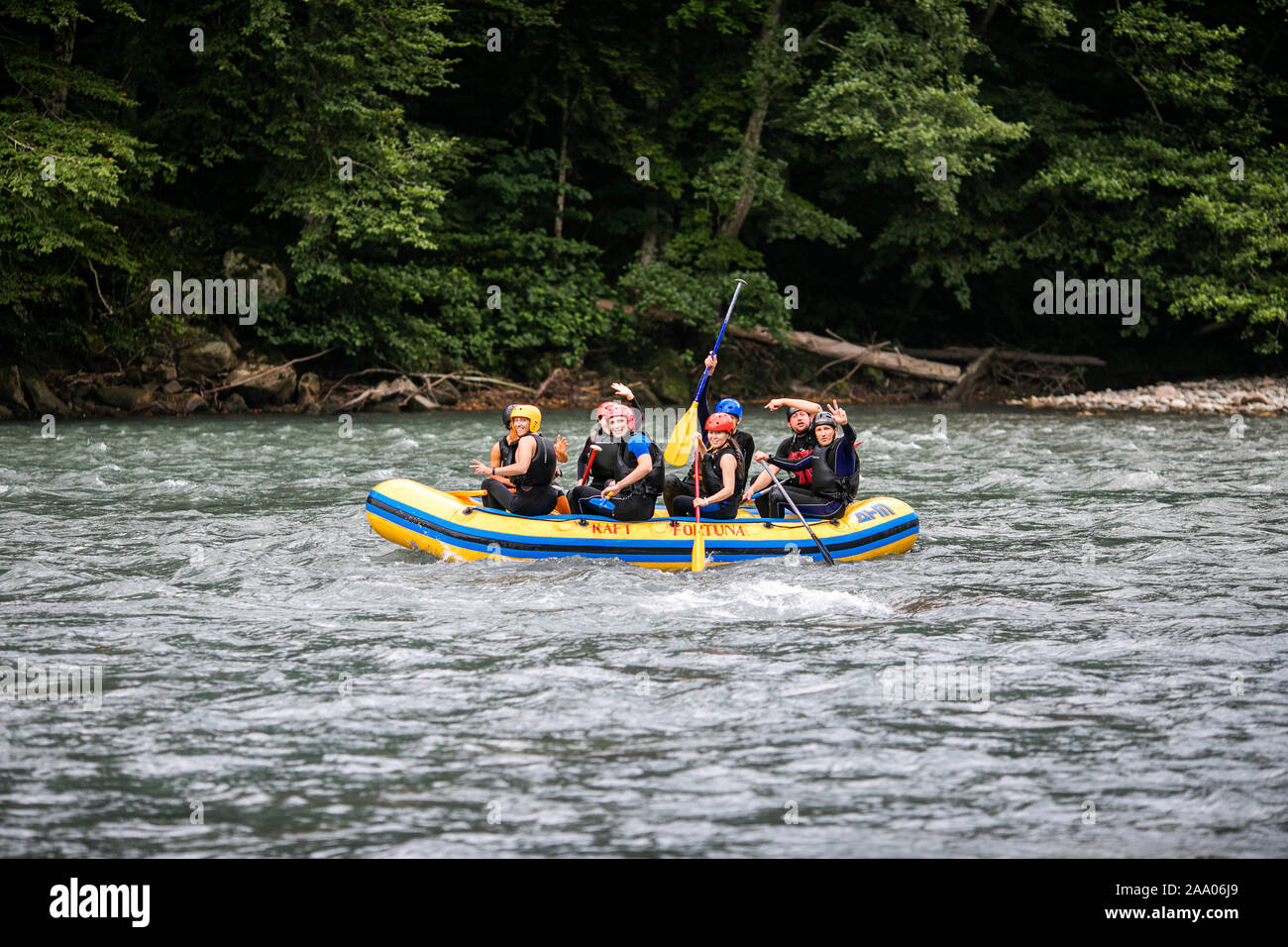 Group of happy people with guide whitewater rafting and rowing on river ...
