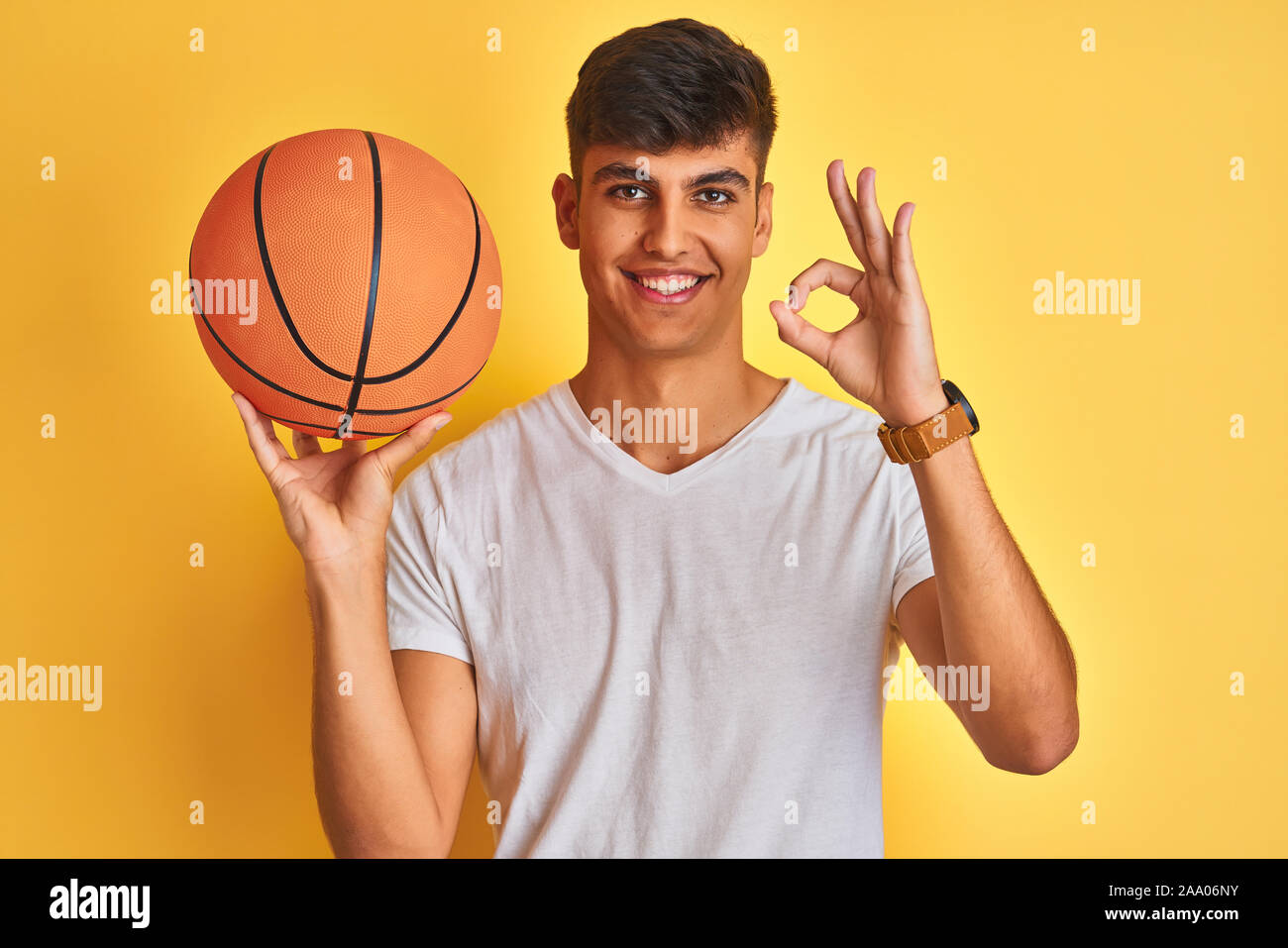 Young indian sportsman holding basketball ball standing over isolated ...
