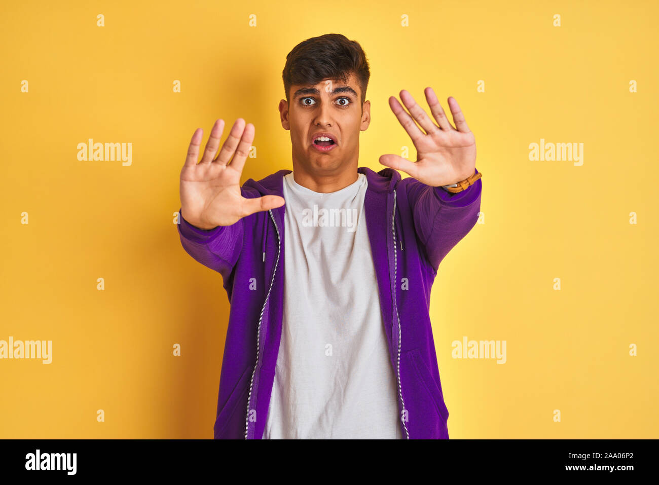Young indian man wearing purple sweatshirt standing over isolated ...