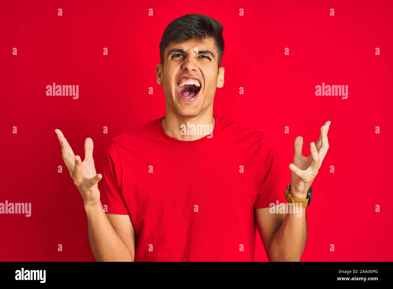 Young indian man wearing t-shirt standing over isolated red background ...