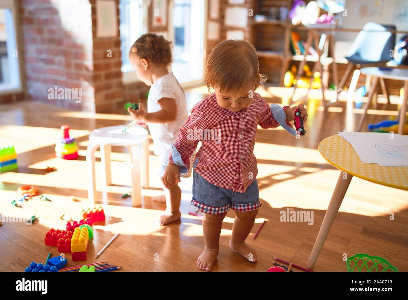 Adorable toddlers playing around lots of toys at kindergarten Stock ...