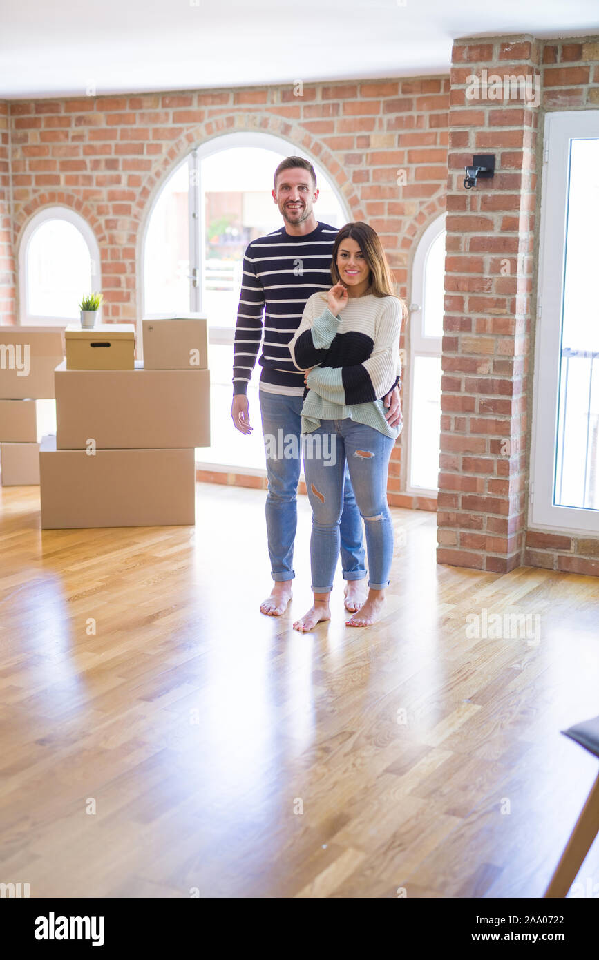 Young beautiful couple hugging at new home around cardboard boxes Stock ...
