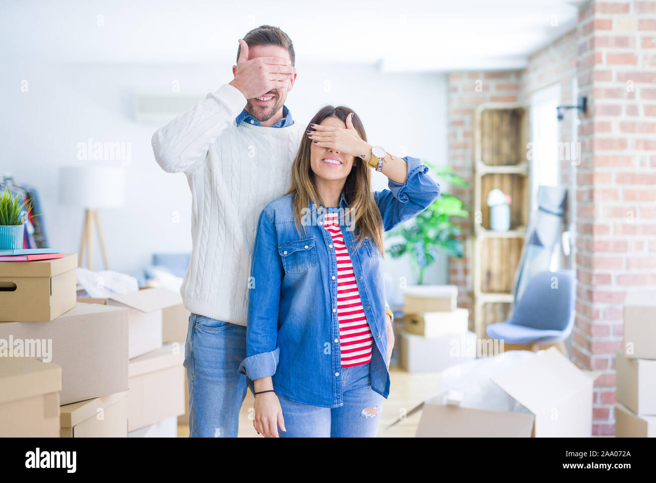 Young beautiful couple standing at new home around cardboard boxes ...