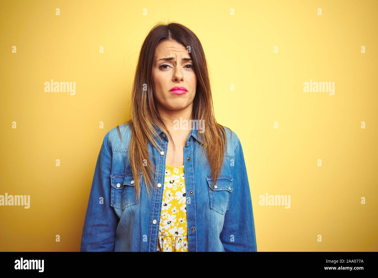 Young beautiful woman standing over yellow isolated background looking ...