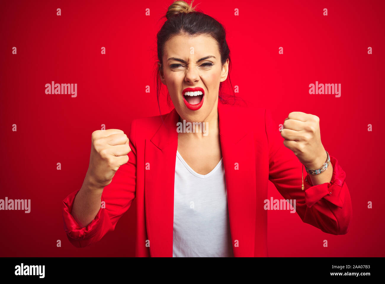 Young beautiful business woman standing over red isolated background ...