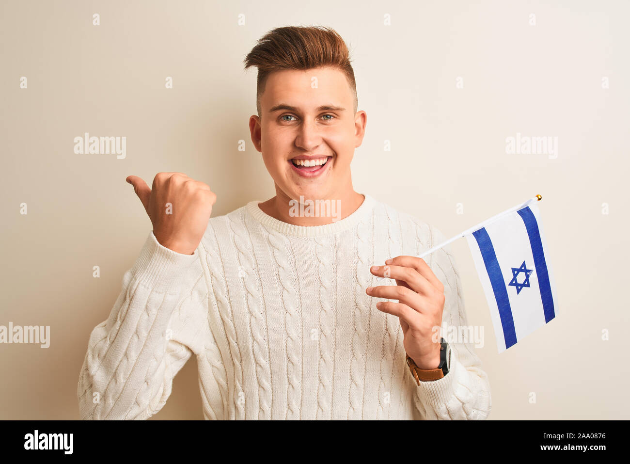 Young handsome man holding Israel Israeli flag over isolated white ...