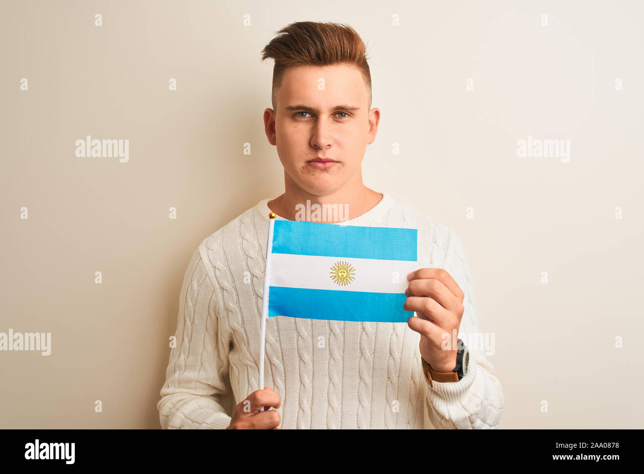 Young handsome man holding Argentinian Argentina flag over isolated ...