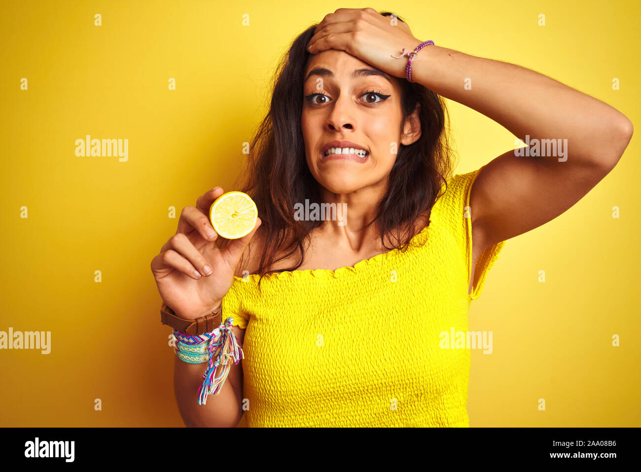 Young beautiful woman holding middle lemon standing over isolated ...
