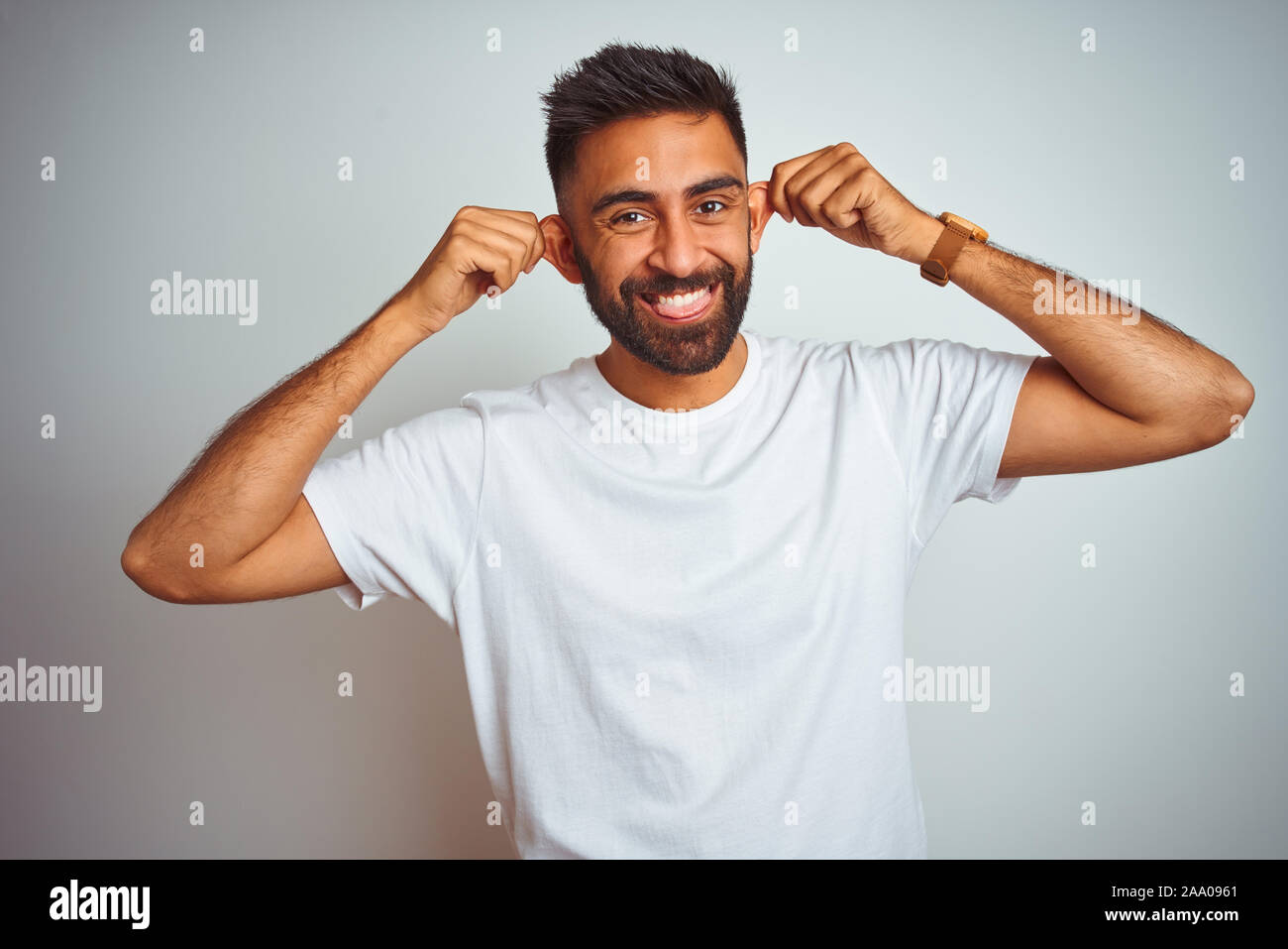 Young indian man wearing t-shirt standing over isolated white ...