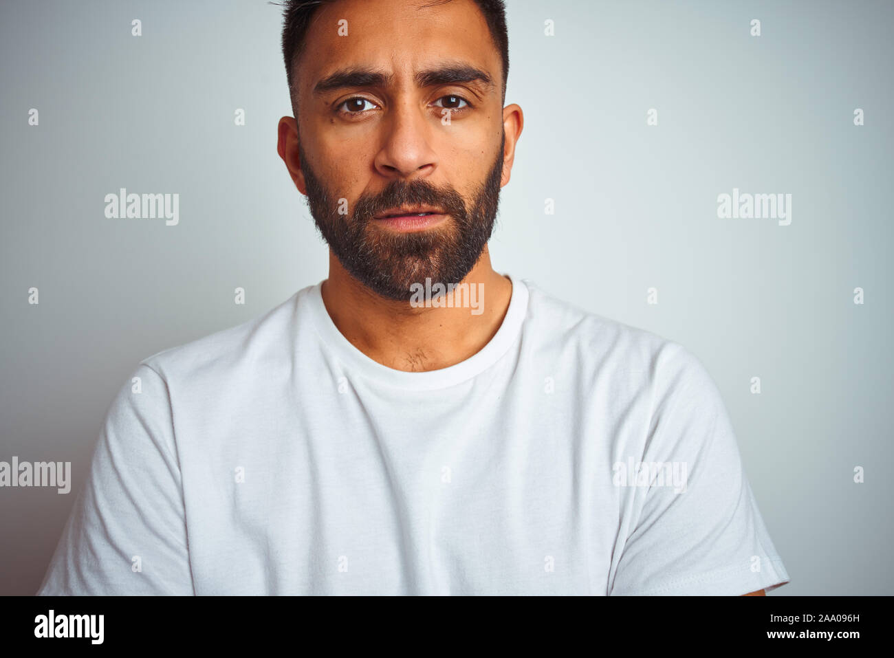Young indian man wearing t-shirt standing over isolated white ...