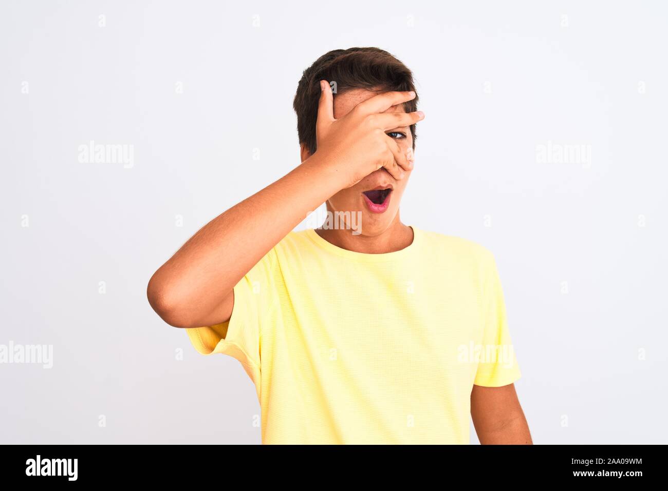 Handsome teenager boy standing over white isolated background peeking ...