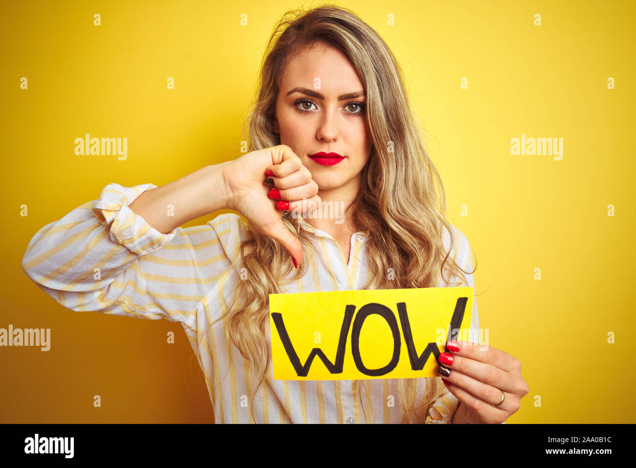 Beautiful woman holding amazed wow surprise banner over isolated yellow ...