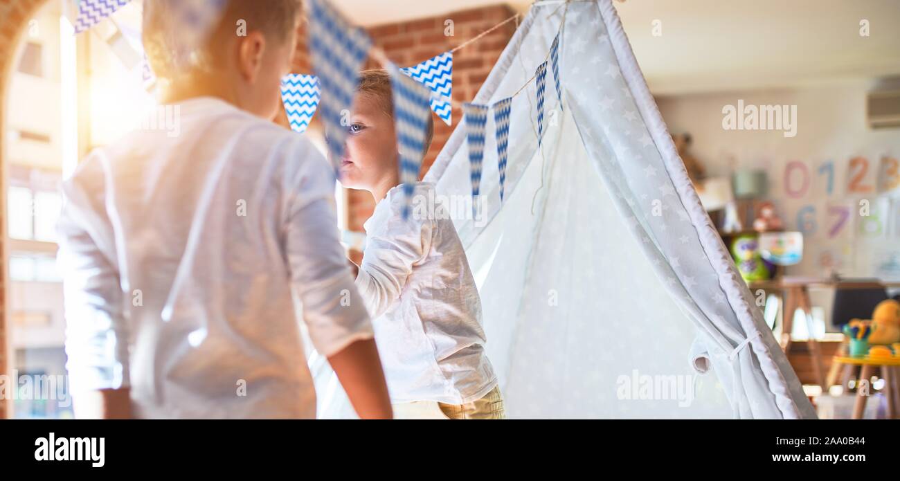 Adorable blonde twins playing inside tipi around lots of toys at ...