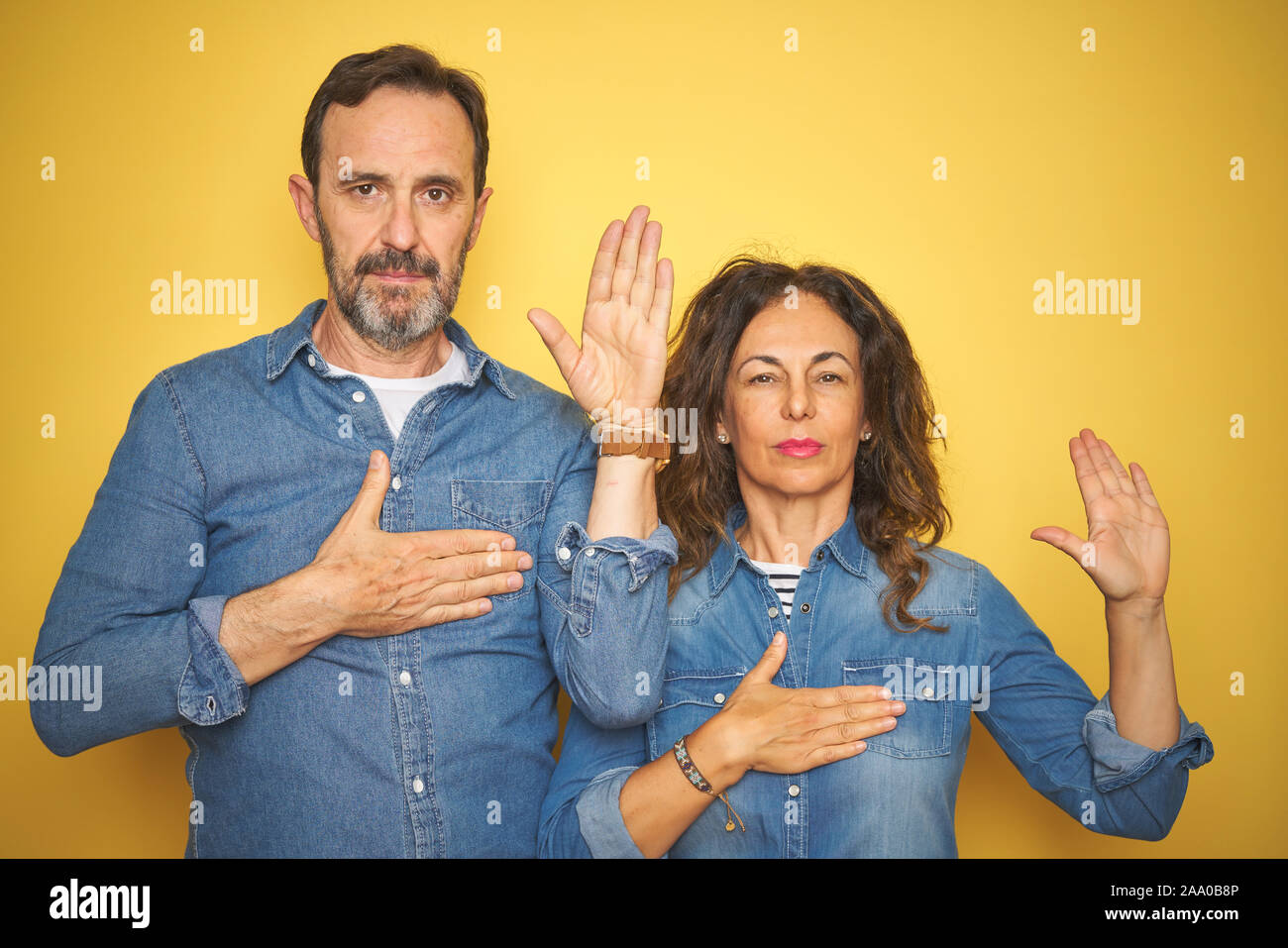 Beautiful middle age couple together standing over isolated yellow ...