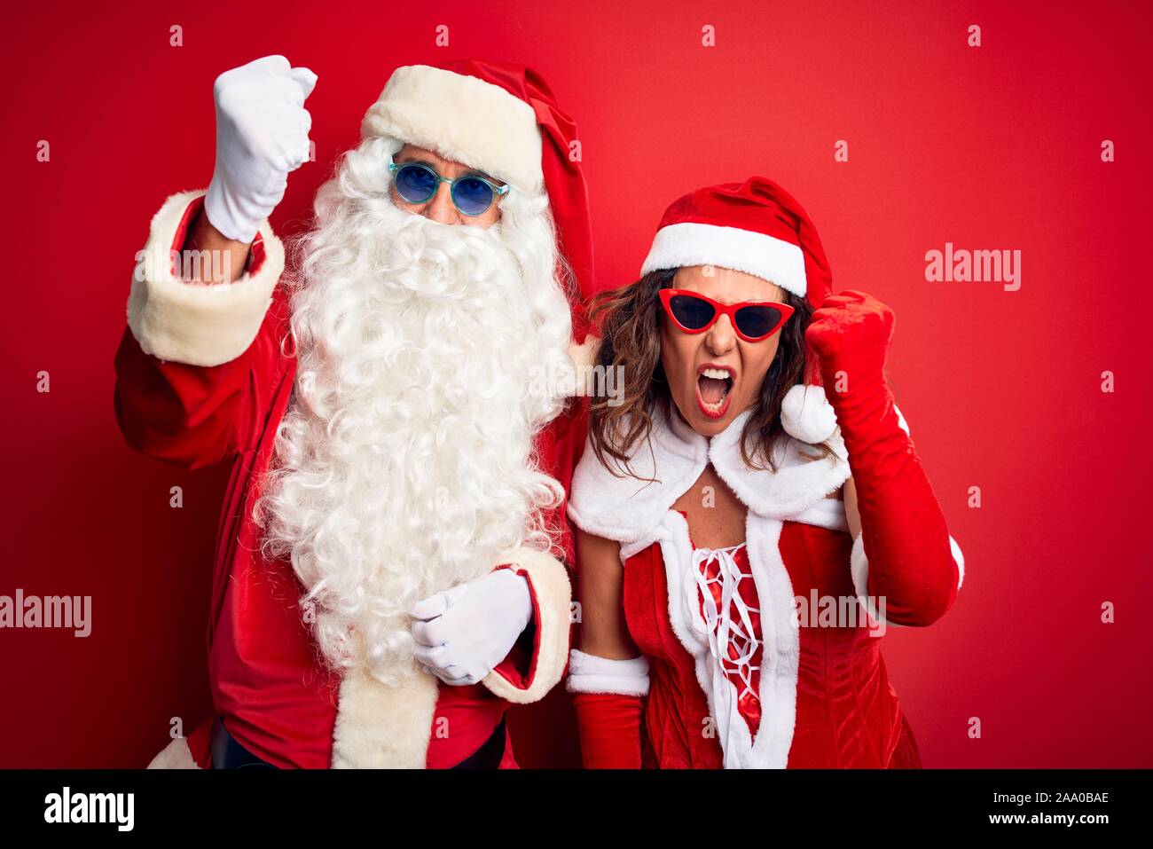 Middle age couple wearing Santa costume and sunglasses over isolated ...