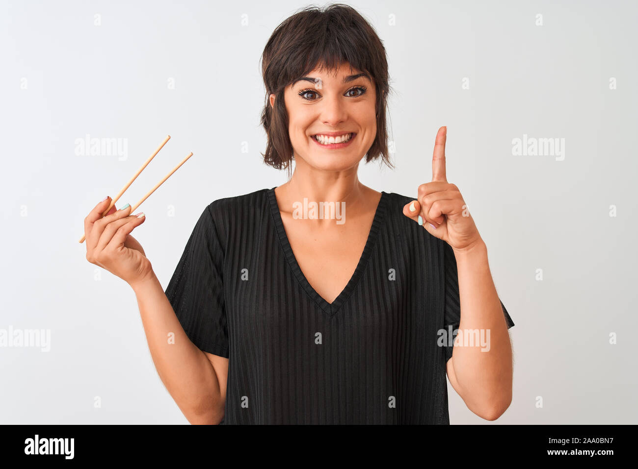 Young beautiful woman holding chopsticks standing over isolated white ...