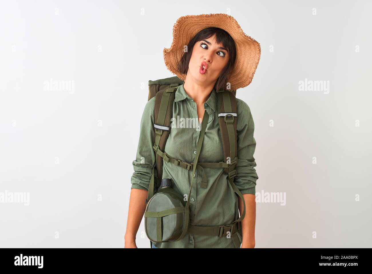 Hiker woman wearing backpack hat and water canteen over isolated white background making fish ...