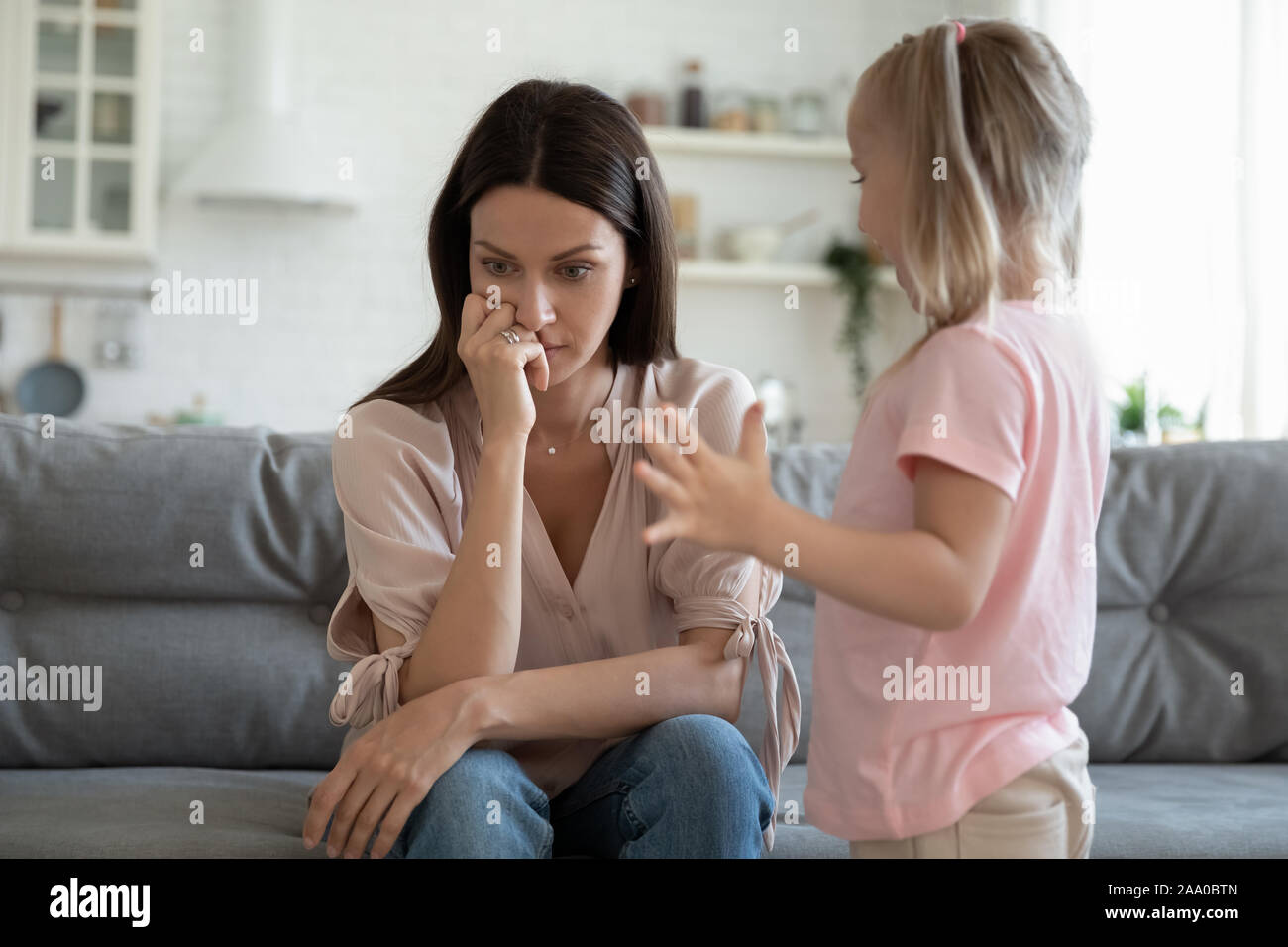 Stressed thoughtful 30s mother ignoring playful happy small daughter ...