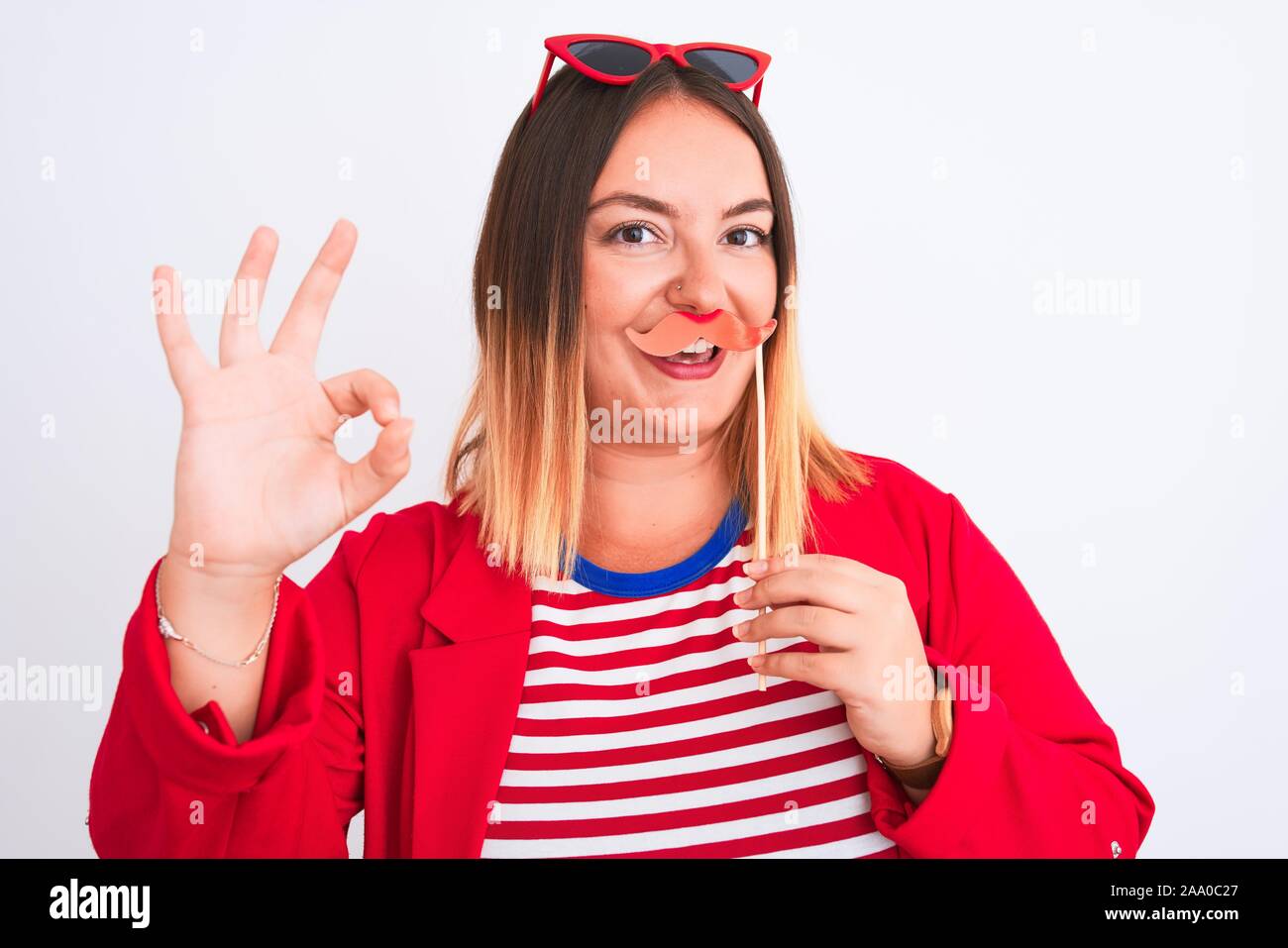 Young beautiful woman holding fanny party mustache standing over ...