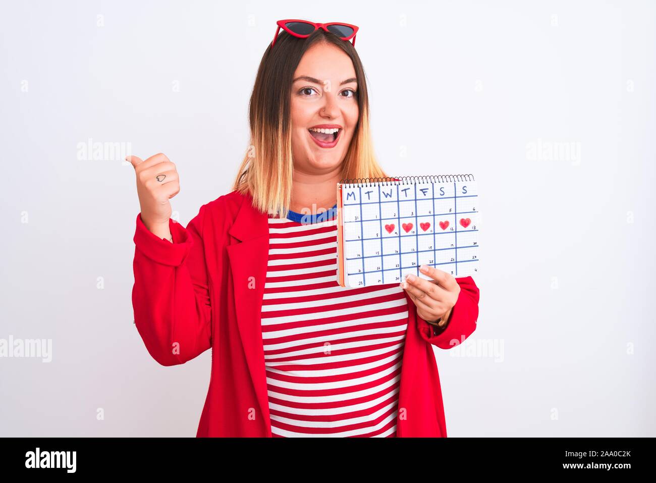 Young beautiful woman holding period calendar standing over isolated ...